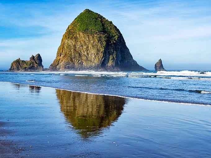 Haystack Rock's mirror image in the wet sand creates a perfect symmetry that photographers dream about capturing.