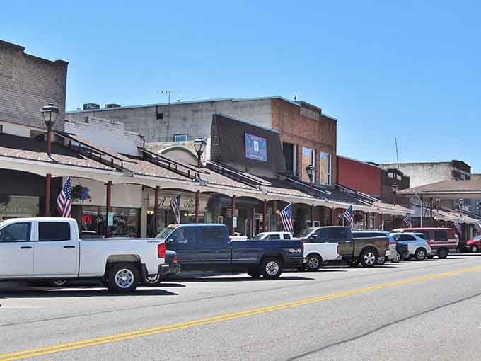 Angle-parked trucks and covered sidewalks create that authentic small-town scene where neighbors still stop to chat on the street.