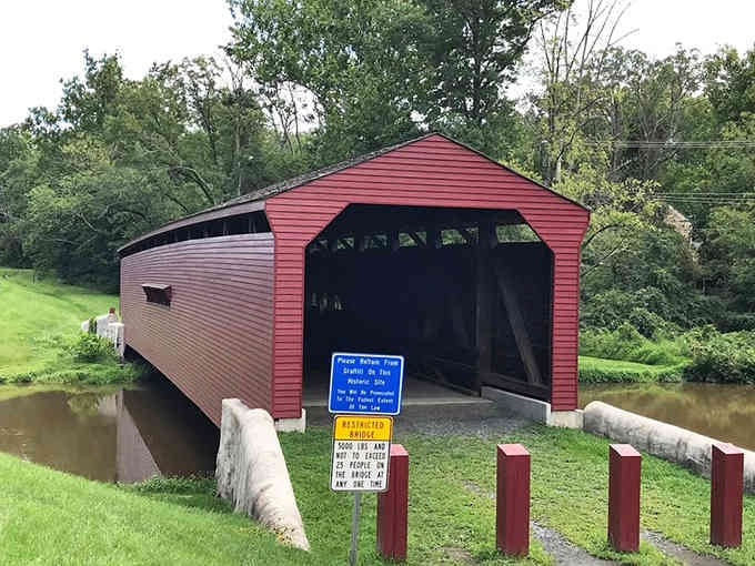 The historical marker welcomes you to cross this charming span, where grass meets water in peaceful countryside perfection.