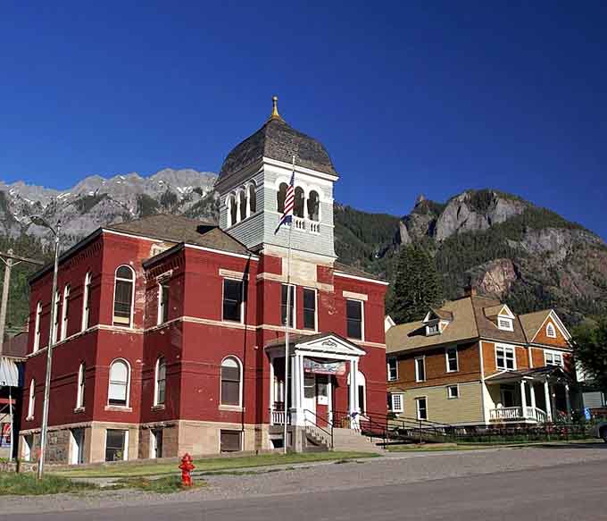 That historic red courthouse stands proud against mountain peaks, reminding everyone that civic pride never goes out of style.