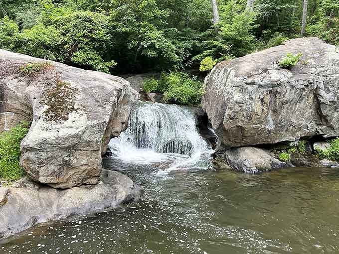Powerful waterfall thunders down cliff face into an inviting emerald pool surrounded by ancient forest.