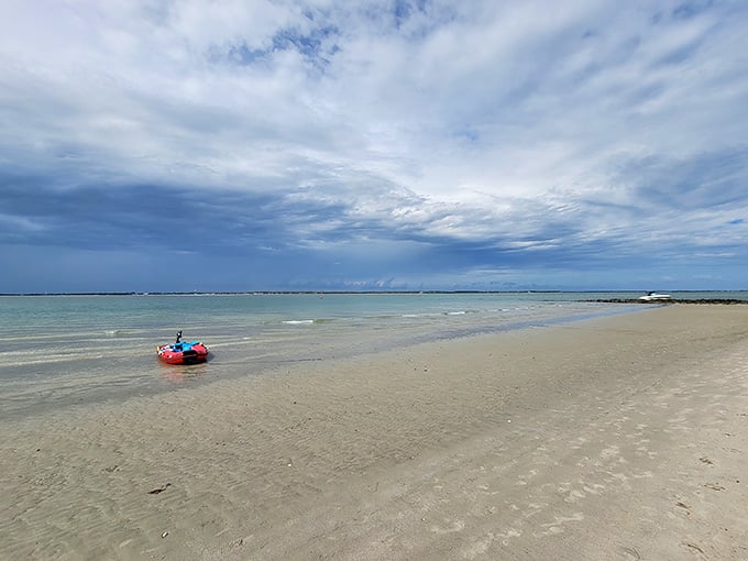 Pristine shoreline stretches endlessly while shallow turquoise water sparkles like someone scattered diamonds across the surface.