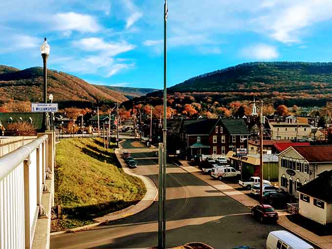 Mountains embrace the town like protective arms, with autumn colors splashing across hillsides that would make Bob Ross reach for his brushes.