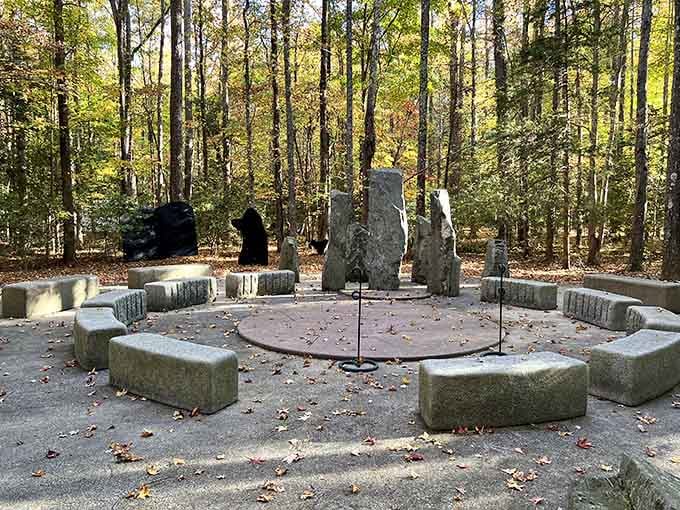 Stone circles create a mysterious gathering space among autumn leaves, inviting quiet contemplation beneath towering trees overhead.