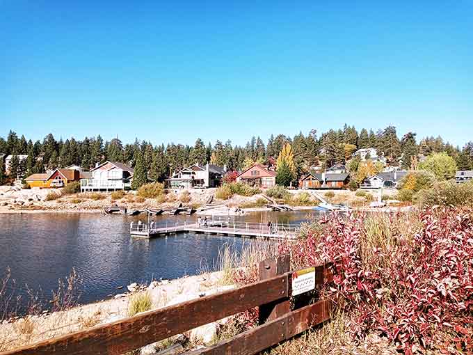 Autumn colors frame the lakeside homes where docks reach into mirror-still water reflecting the surrounding forest and sky.