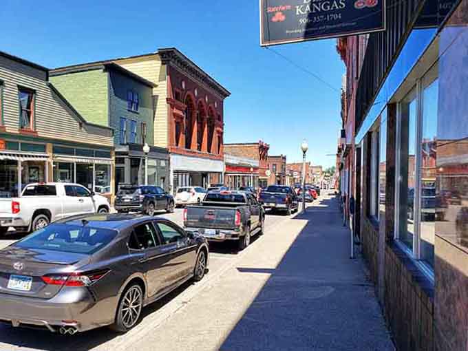 The sidewalk stretches past storefronts that have served generations, their brick facades warm in the afternoon sunlight.