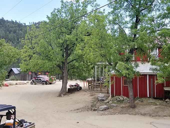Shaded dirt roads and rustic red buildings create a peaceful mountain retreat far from desert heat below.