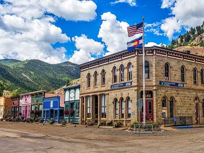 Historic stone buildings stand proudly beneath dramatic San Juan peaks, their flags waving like they're celebrating another perfect day.