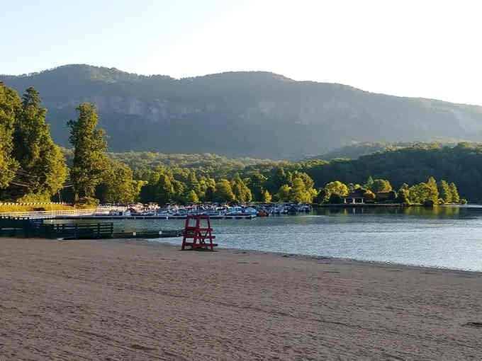 That sandy beach stretches along calm water with mountains watching over like protective old friends nearby.