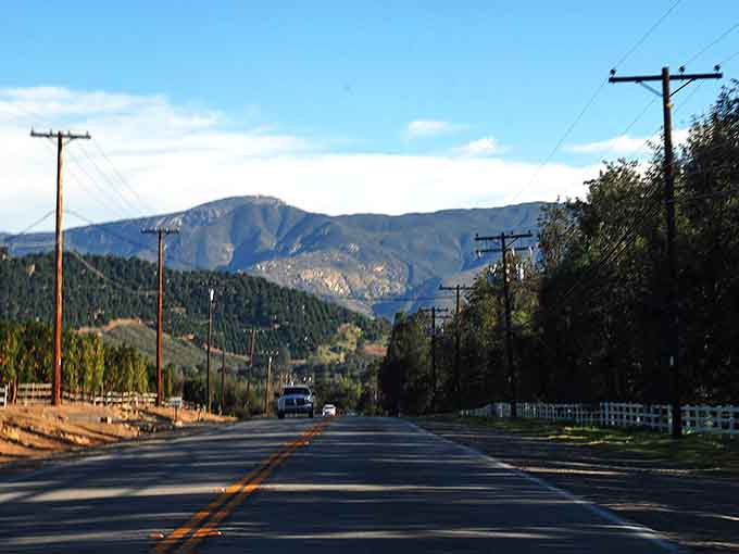 Telephone poles march toward distant peaks, framing a view that belongs on a vintage travel poster.