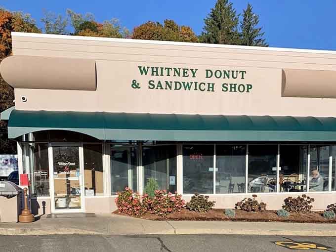 That classic green-striped awning shelters a daytime haven where donuts and sandwiches share equal billing beautifully.