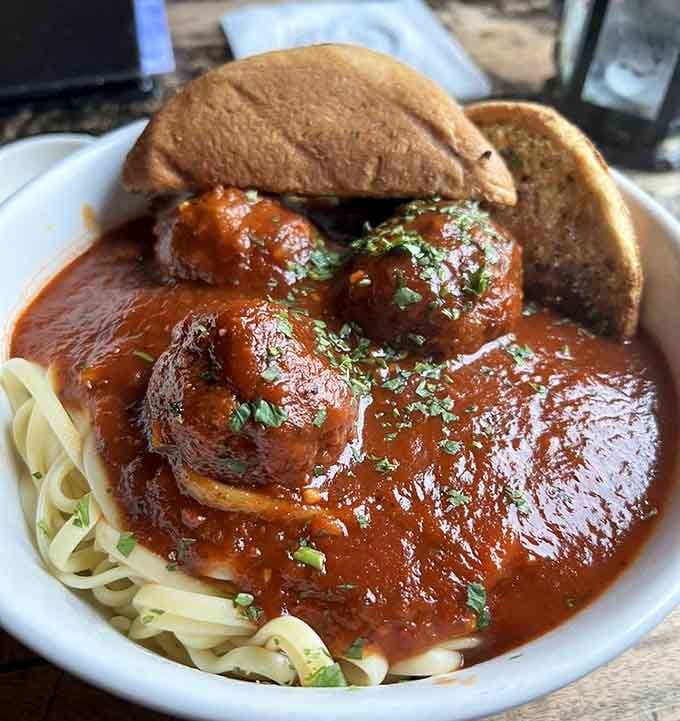 Spaghetti and meatballs swim in rich sauce, comfort food elevated to an art form worth writing poetry about.