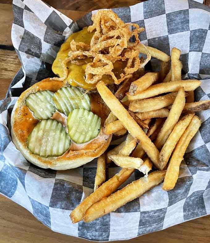 The Campfire Burger arrives with crispy onion strings piled high, pickles at attention, and fries for days. Perfection achieved.