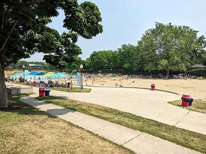 Mature trees provide natural shade across sprawling grounds where families claim their territory for lazy summer days that stretch deliciously long.