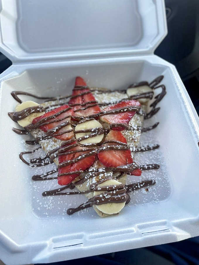 Strawberries and bananas nestled in a delicate crepe with chocolate sauce, proving that simple combinations create magic.