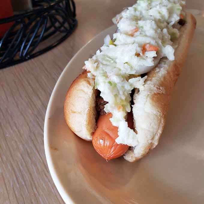 That mountain of slaw on a hot dog is either genius or madness, and honestly, it's probably both in the best way.