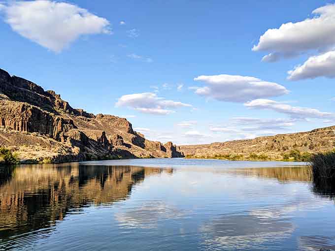 Mirror-smooth water reflects the cliffs, creating a postcard moment where chaos once ruled absolutely supreme.
