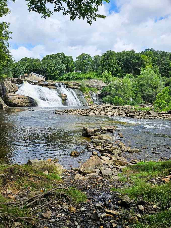 The cascading waterfalls and lush green trees create a stunning, peaceful backdrop for a relaxing afternoon by the river&rsquo;s edge.