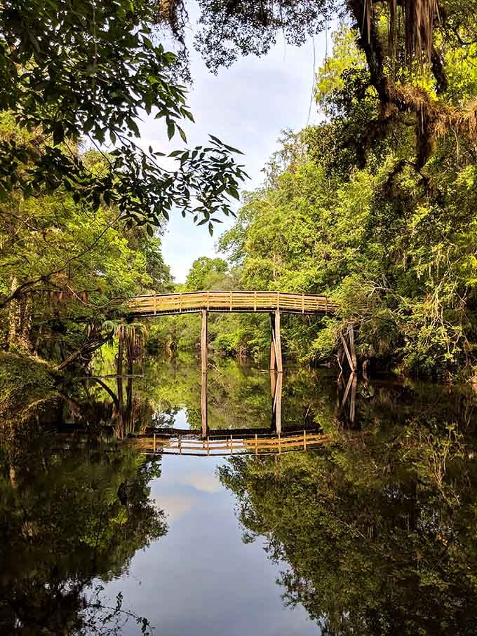 The arched bridge reflects perfectly in mirror-still water, creating a scene worthy of a Monet painting.