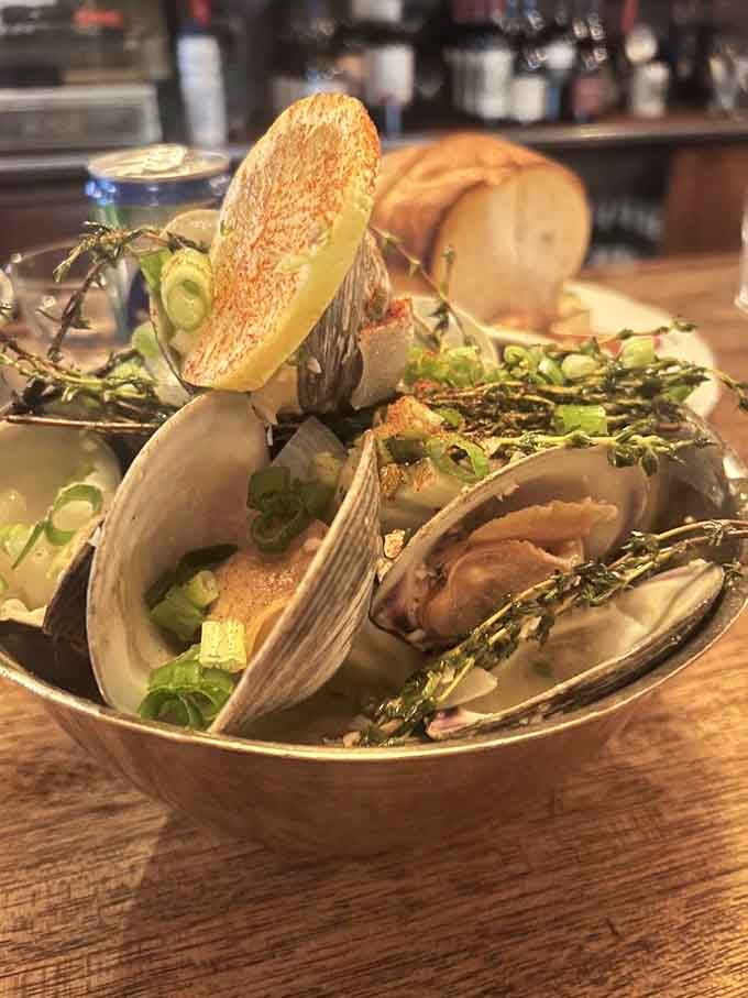 Fresh clams in white wine herb butter broth, perfect for soaking up with crusty bread.