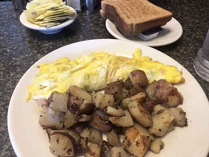 That omelet's so fluffy it might float away, paired with home fries that actually earned their name.