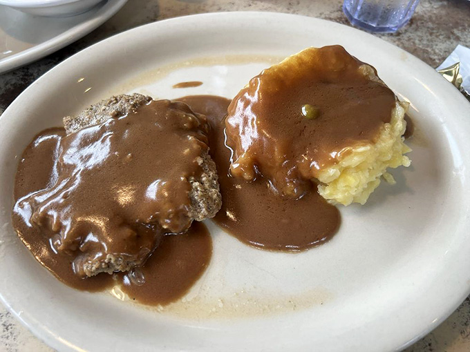 Salisbury steak drowning in brown gravy with real mashed potatoes: comfort food at its most unapologetic.