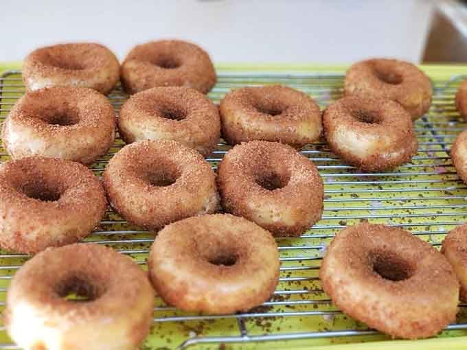 Cinnamon sugar donuts cooling on racks, looking like they just won the lottery of breakfast pastries.