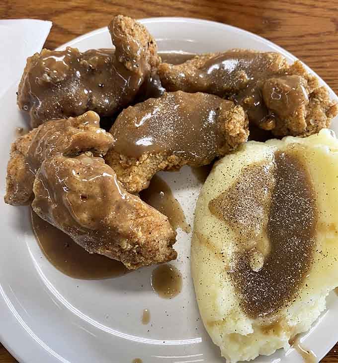 Golden fried chicken pieces swimming in gravy represent everything right about traditional Midwestern cooking done properly.