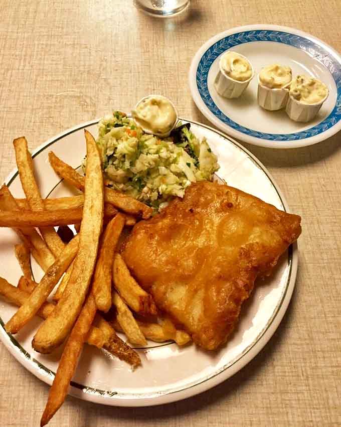 The holy trinity of fried fish happiness: crispy cod, golden chips, and tartar sauce worth writing home about.