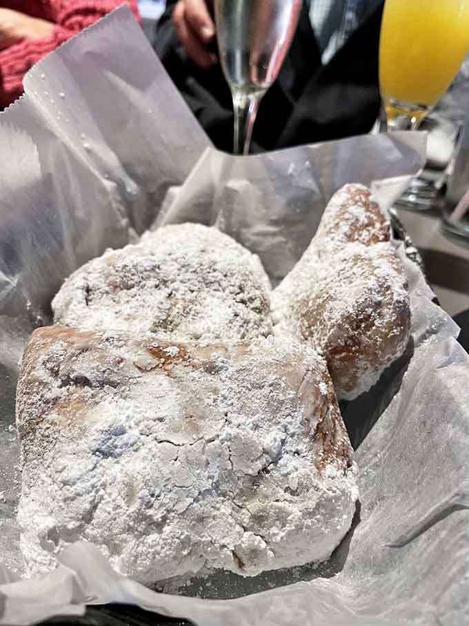 These beignets arrive buried under powdered sugar like edible snowdrifts, sweet and impossible to share without getting messy.