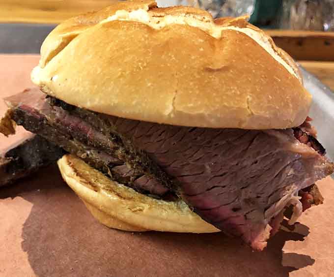 That brisket sandwich is stacked so high it requires engineering skills and possibly a structural permit to eat properly.