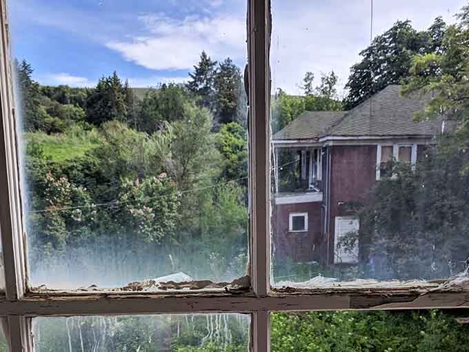 The view from inside reveals neighboring buildings through dusty glass, a reminder that life goes on outside these walls.