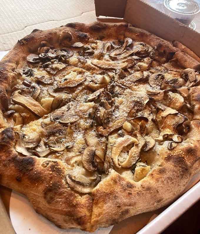 Earthy mushrooms blanketing creamy cheese on wood-fired crust: proof that vegetarian options can steal the show without even trying.