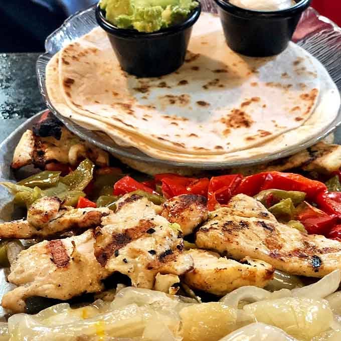 Sizzling fajitas arriving at your table like a Broadway entrance, complete with caramelized peppers and perfectly charred chicken.