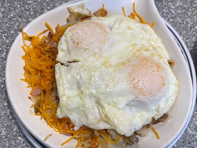 Hash browns topped with eggs and melted cheese create a breakfast skillet that requires both strategy and serious appetite.