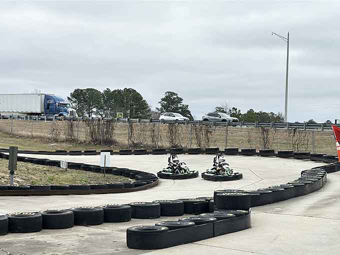 Two racers battle it out on this outdoor course while highway traffic zooms by in the background.