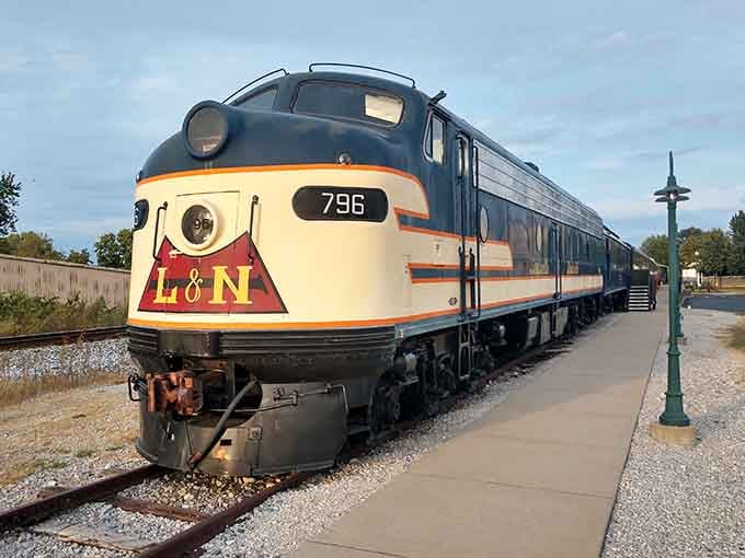The classic L&N locomotive's cream and burgundy paint scheme gleams beside the peaceful walking path at sunset.