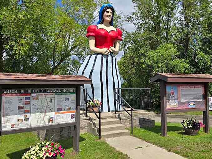 Lucette stands gracefully in her striped skirt, proving every great man needs an equally great woman beside him.