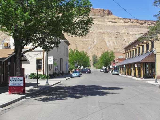 Desert cliffs rise behind main street like ancient sentinels guarding this fruit-growing valley's sweetest secrets and peach orchards.