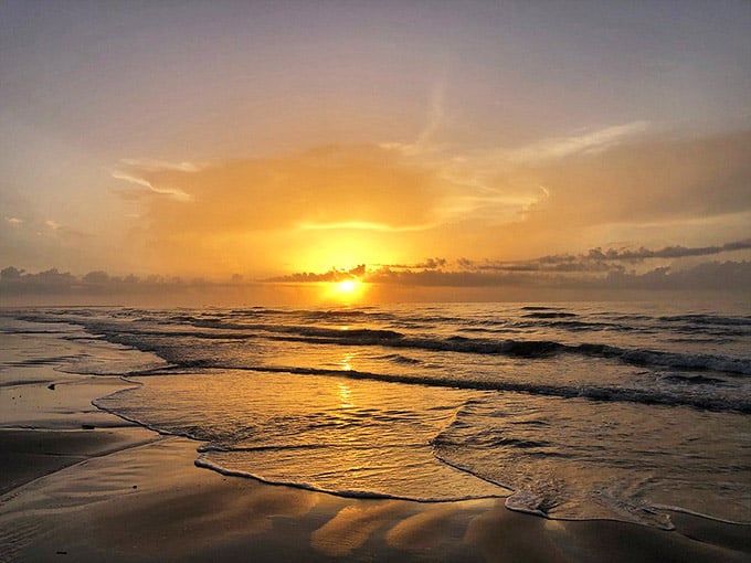 Golden hour transforms the Gulf into liquid fire, painting the sand with shadows that dance with each wave.