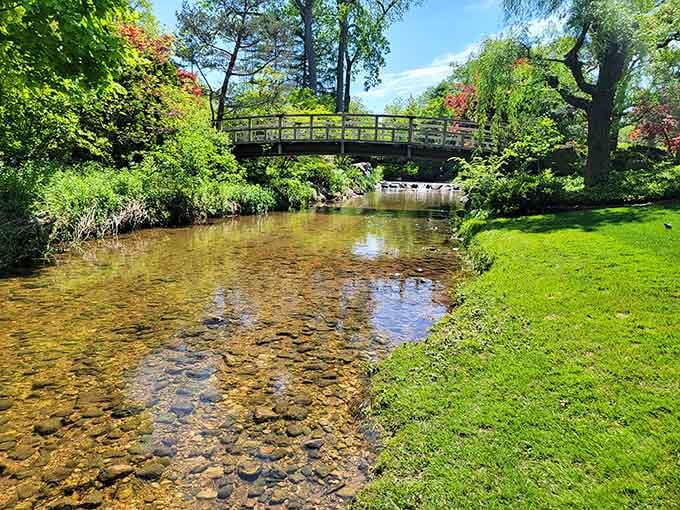 A gentle stream meanders through this serene landscape, crossed by an arched bridge that invites quiet contemplation and reflection.