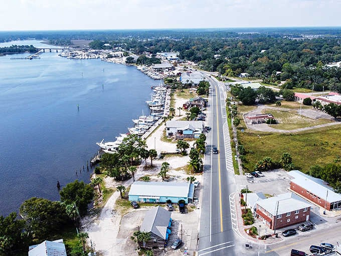 The waterfront road stretches into the distance, lined with boats ready for tomorrow's catch under blue skies.