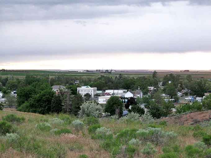 Storm clouds gather over wheat fields and scattered trees in a landscape that's been feeding America for generations.