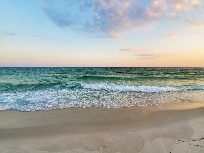 Sunset paints the Gulf in soft pastels while gentle waves kiss the shore in this picture-perfect coastal moment.