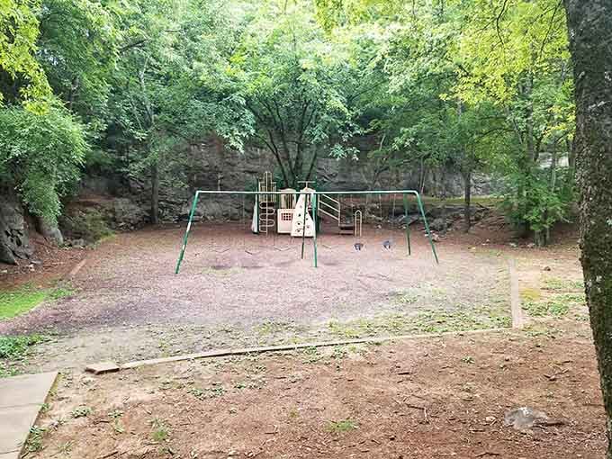Towering quarry walls embrace this shaded play area, offering natural protection and a unique backdrop for swings.