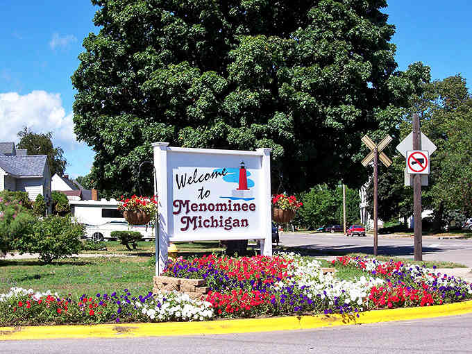 Bright flowers frame this cheerful welcome sign, proving small towns know how to make a memorable first impression.