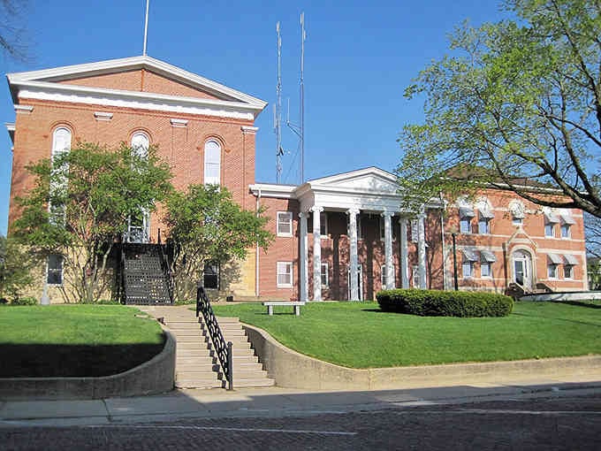 White columns frame red brick elegance, proving that courthouse architecture once meant something more than just functional government buildings.