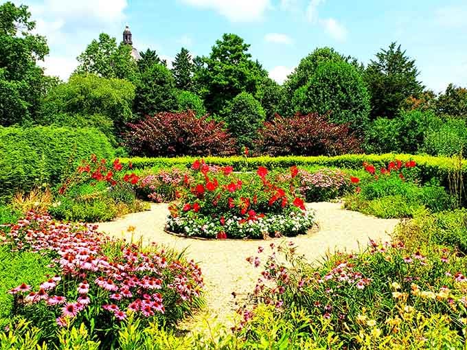 Formal garden beds burst with red flowers and chartreuse foliage, creating layers of color that delight the eye.