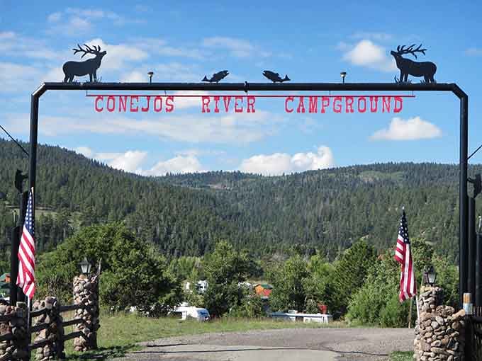Conejos River Campground welcomes you beneath elk silhouettes and American flags, where nature meets no-frills hospitality perfectly.
