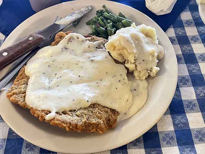 Chicken fried steak buried under peppery white gravy is basically a hug on a plate with mashed potatoes.